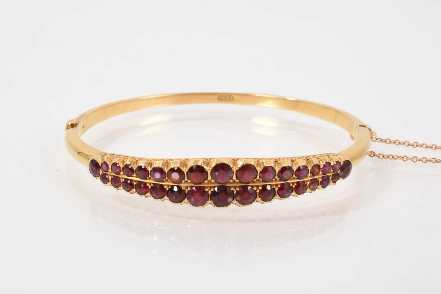 Lot 225 - 18ct gold and garnet bangle